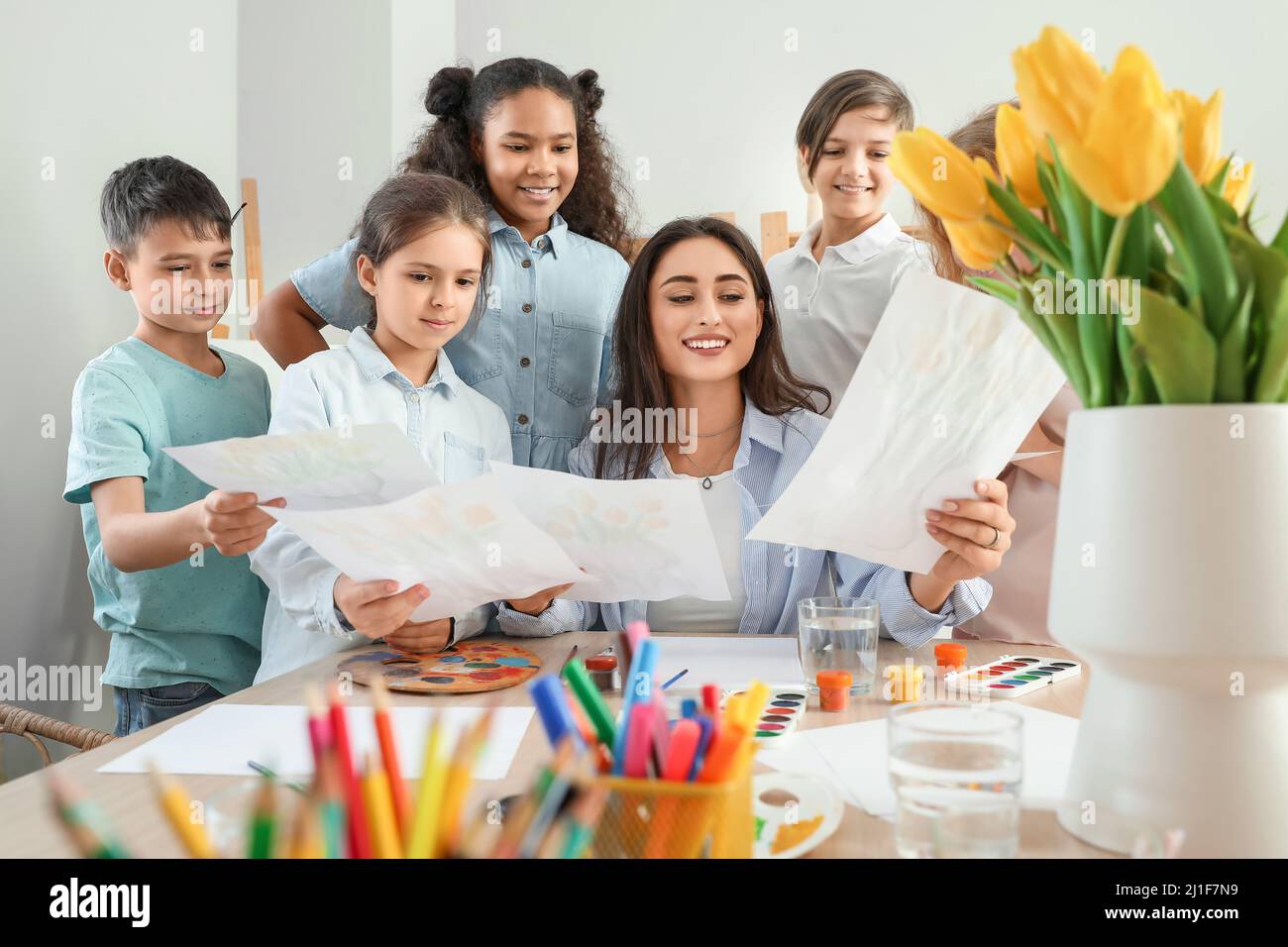 Cute children showing teacher their pictures painted during master ...