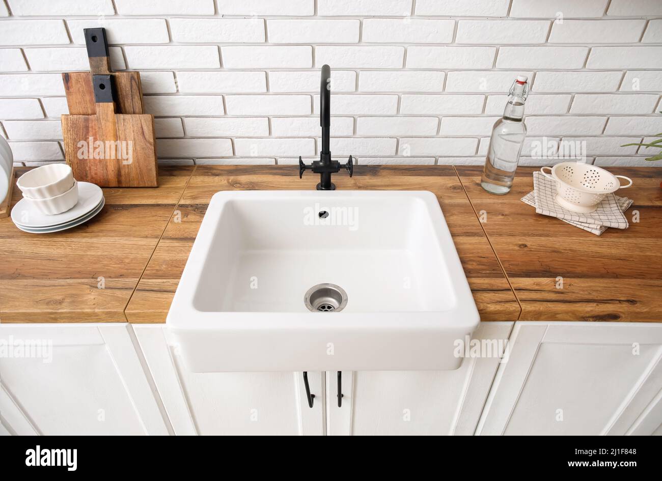 Counters with sink and kitchen utensils near white brick wall Stock ...