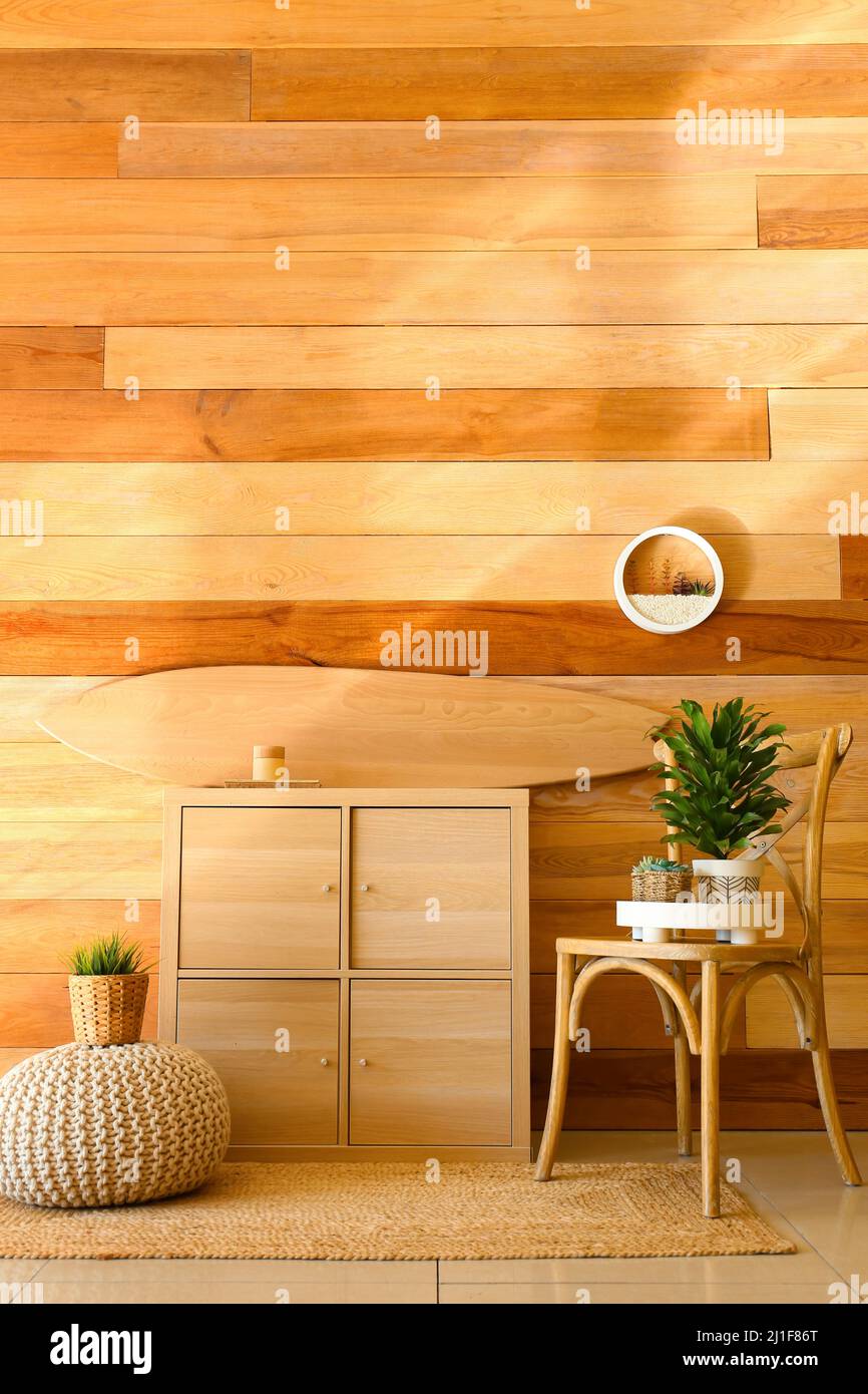 Interior of stylish room with wooden surfboard, commode and chair Stock ...