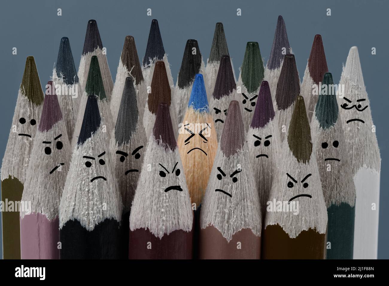 Bright colored bullied pencil among big set of black and white angry ...