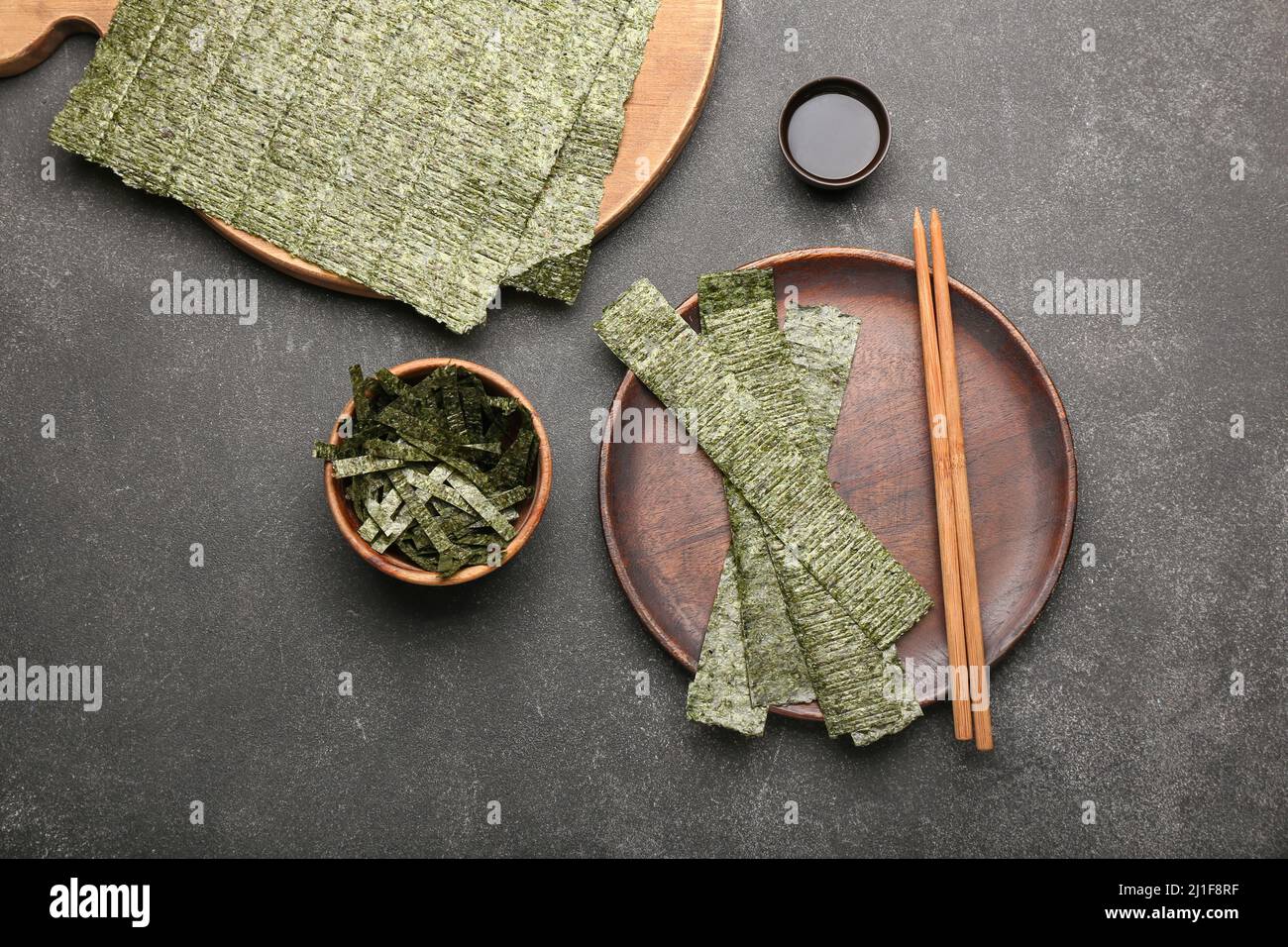 Plate of tasty seaweed sheets and bowl with soy sauce on black ...