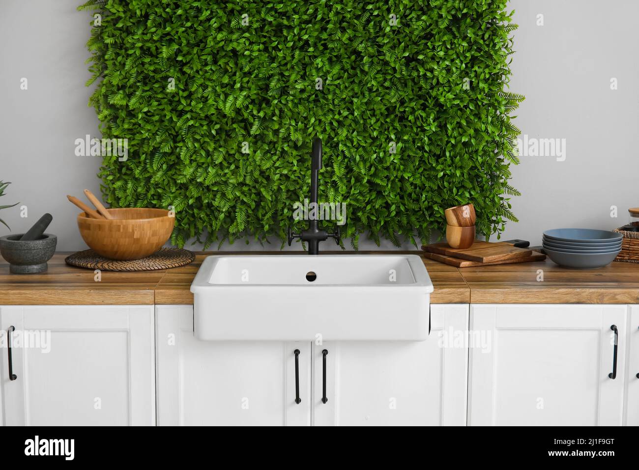 Sink, kitchen utensils and counters near light wall with decorative ...