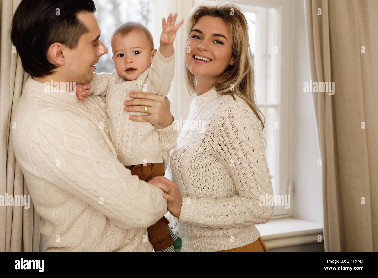 Young and happy family standing beside the window Stock Photo - Alamy