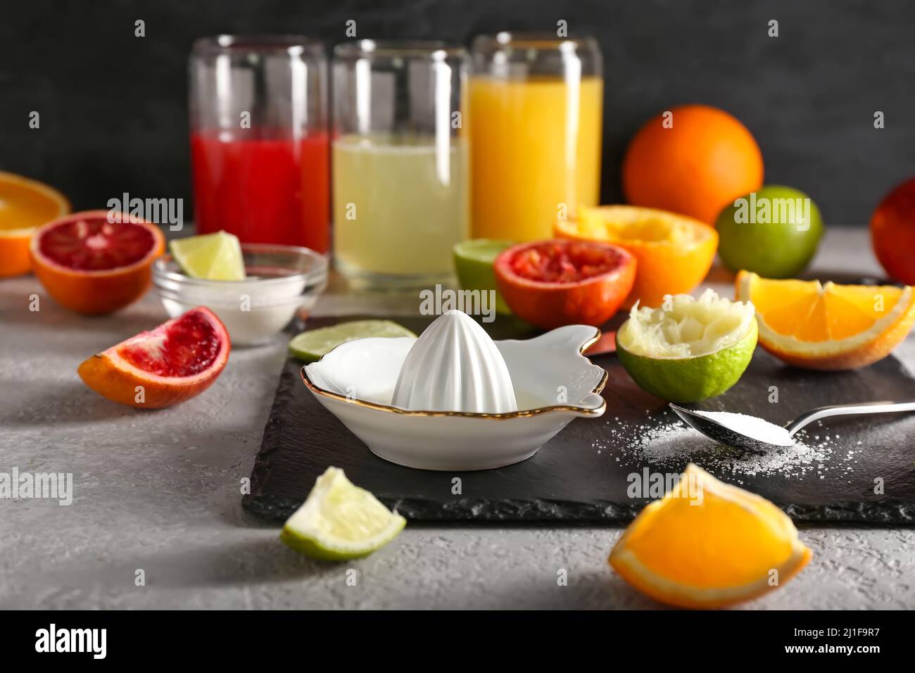 Ceramic juicer, sugar and citrus fruits on grey background Stock Photo ...