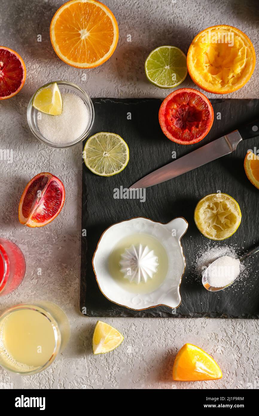 Ceramic juicer, juice, sugar and citrus fruits on grey background Stock ...