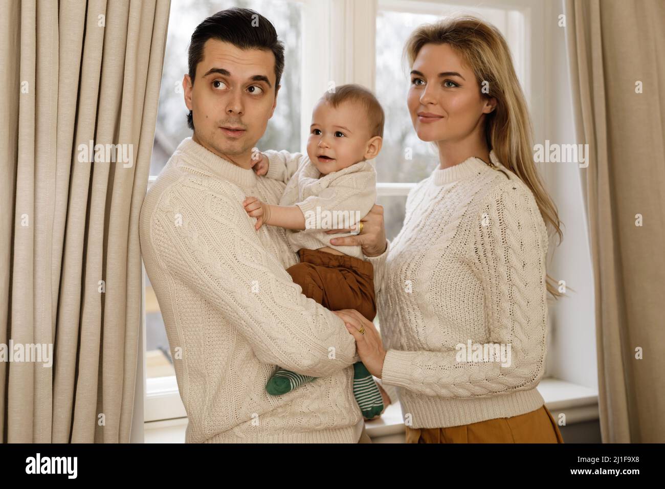 Young and happy family standing beside the window Stock Photo - Alamy