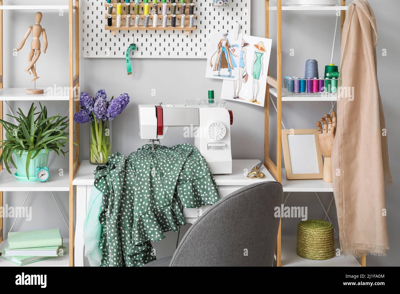 Tailor's workplace with sewing machine and clothes in modern atelier ...