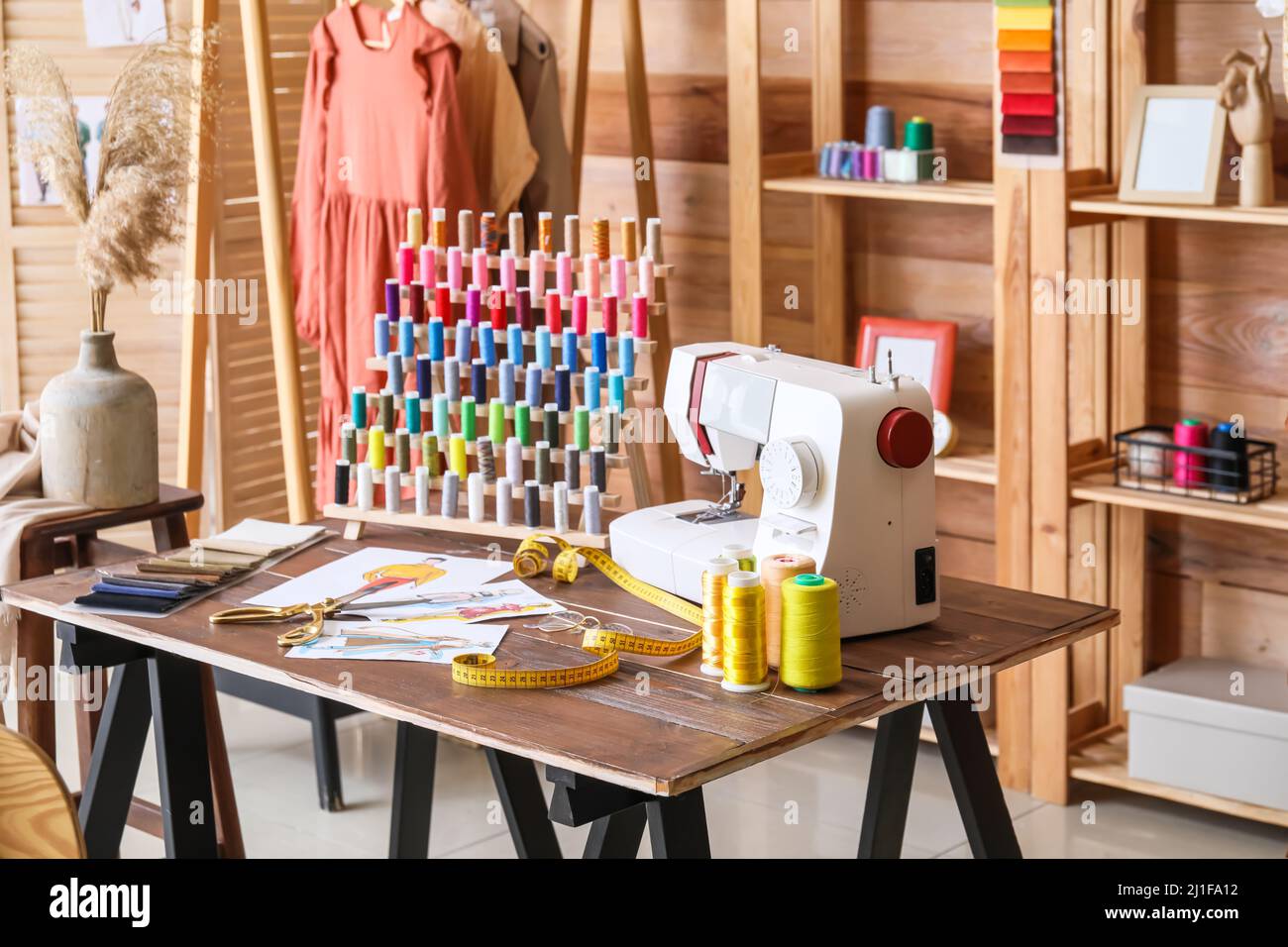 Tailor's workplace with sewing machine, thread spools and sketches in ...