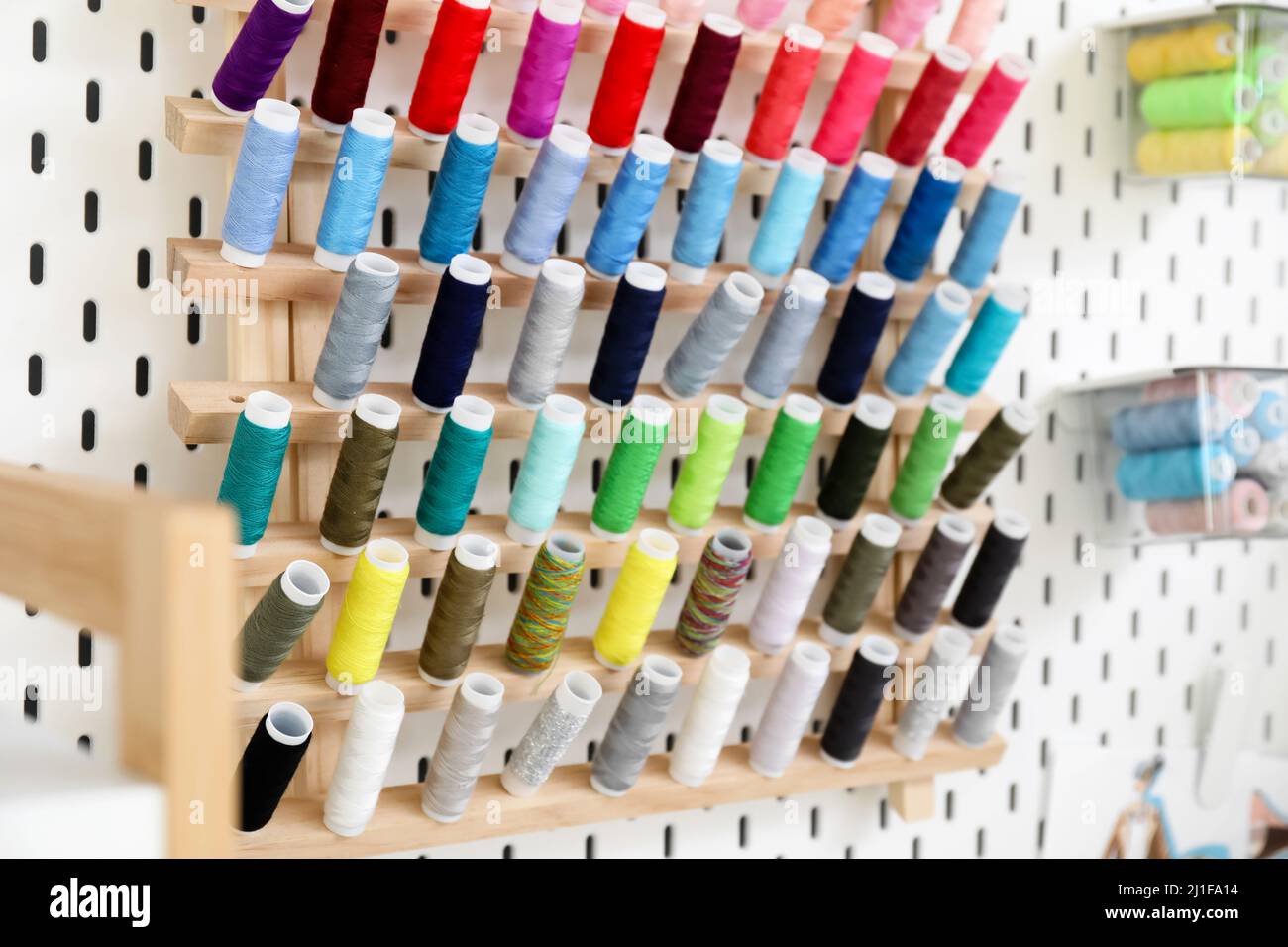 Stand with thread spools hanging on pegboard in atelier, closeup Stock ...