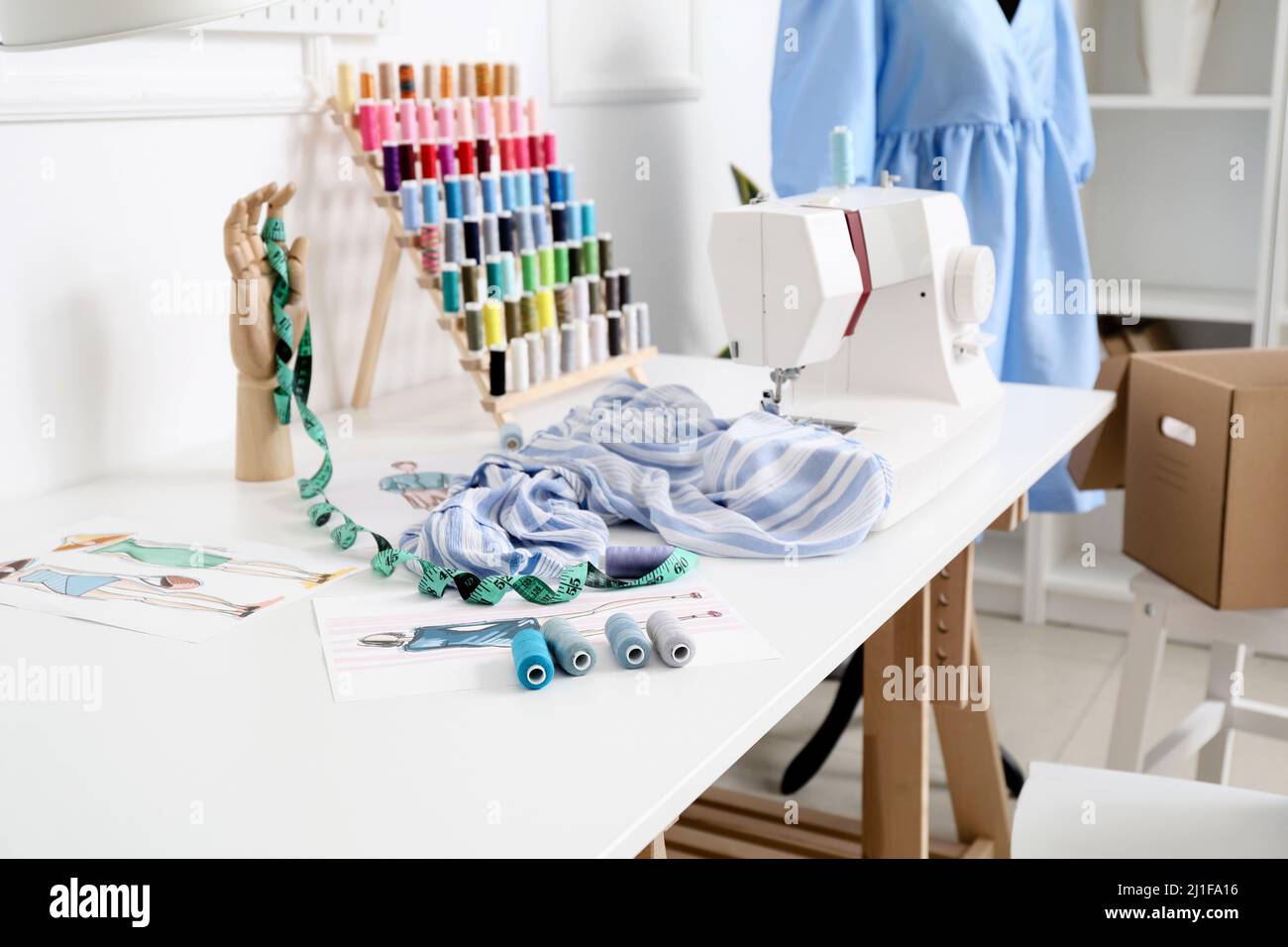 Modern tailor's workplace with sewing machine and thread spools in ...