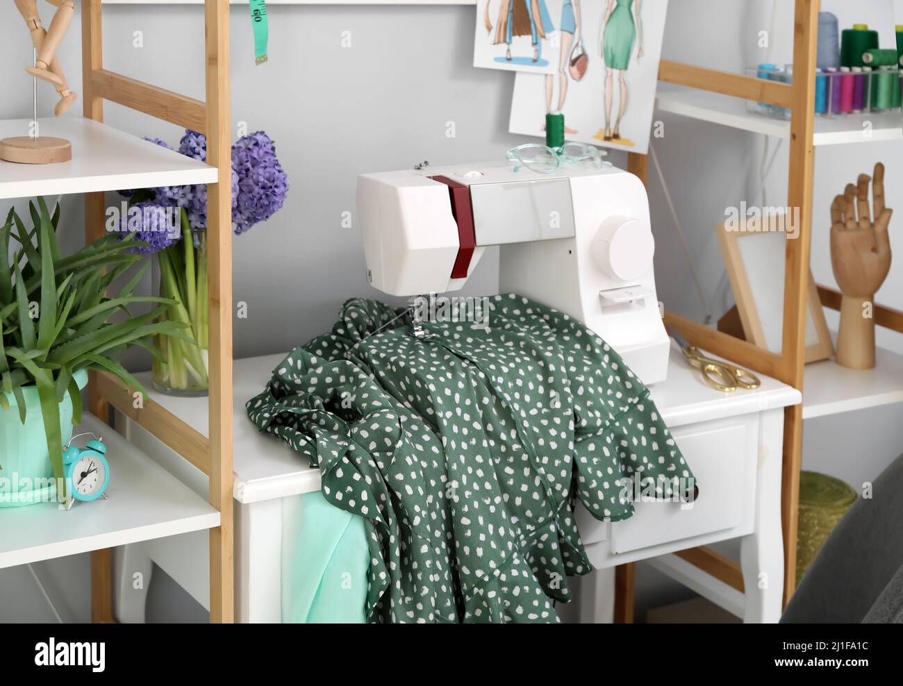 Tailor's workplace with sewing machine and clothes in modern atelier ...