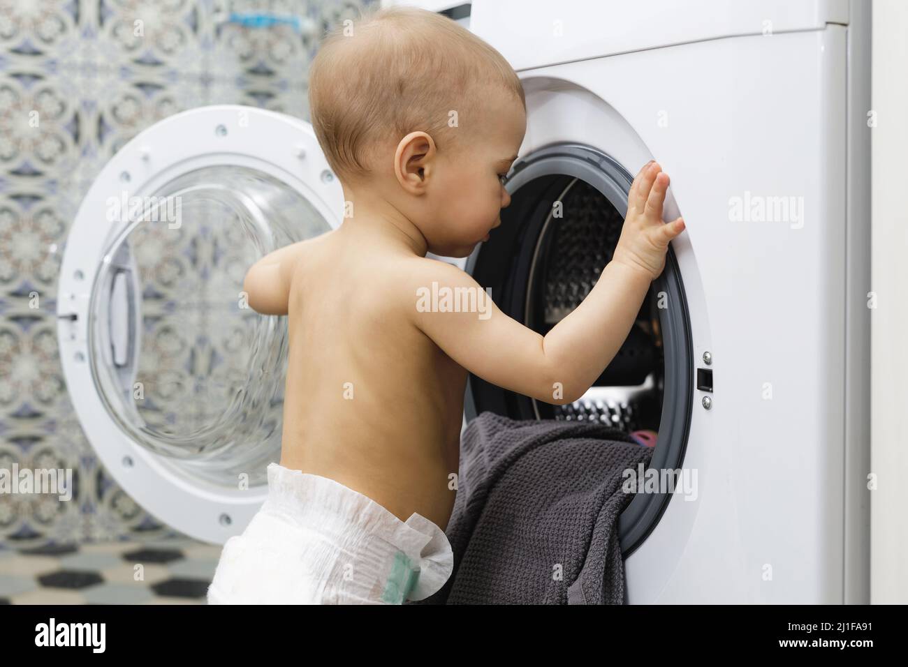 Cute baby boy is looking inside the washing machine Stock Photo - Alamy