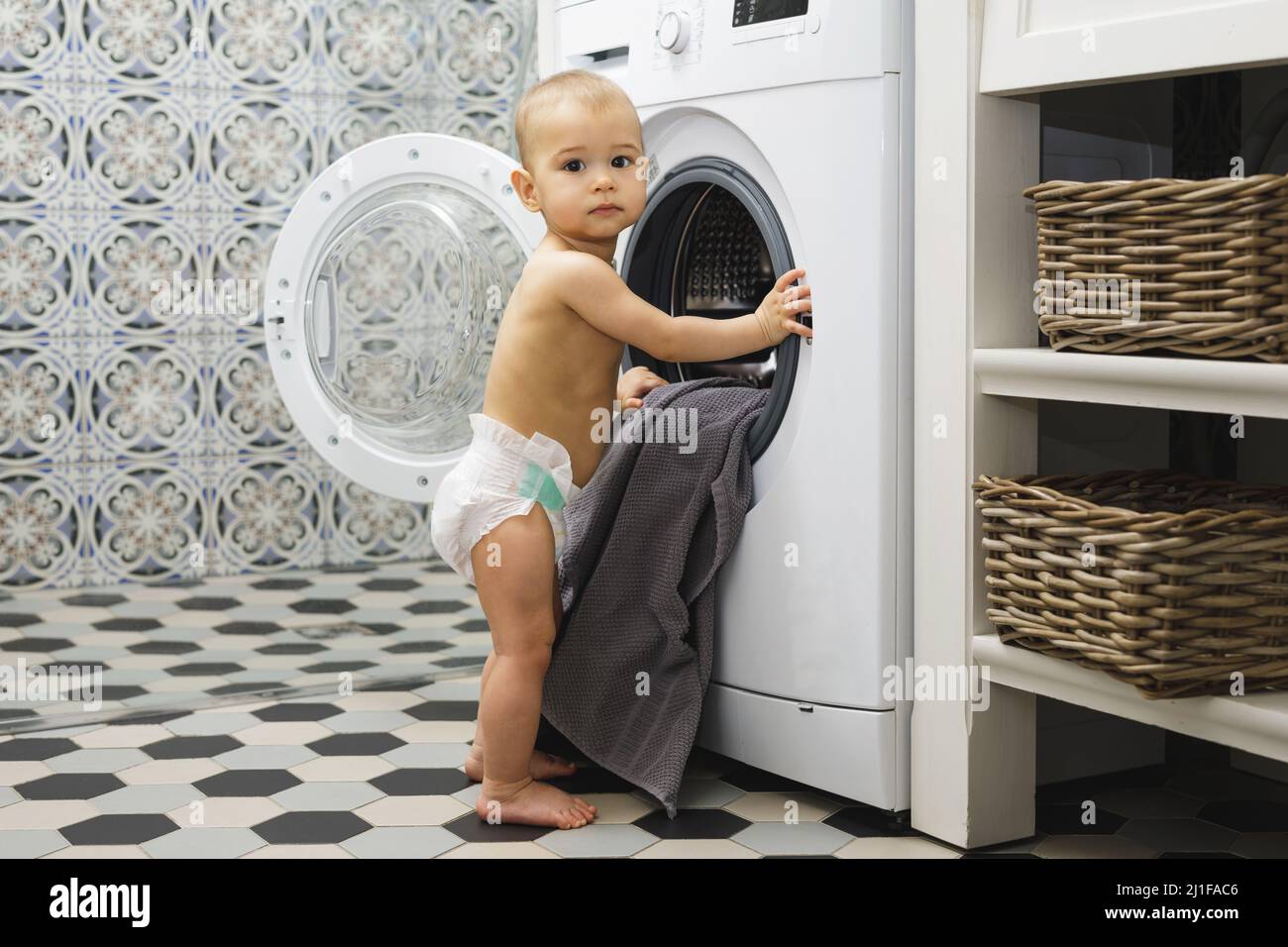 Cute baby boy is looking inside the washing machine Stock Photo - Alamy