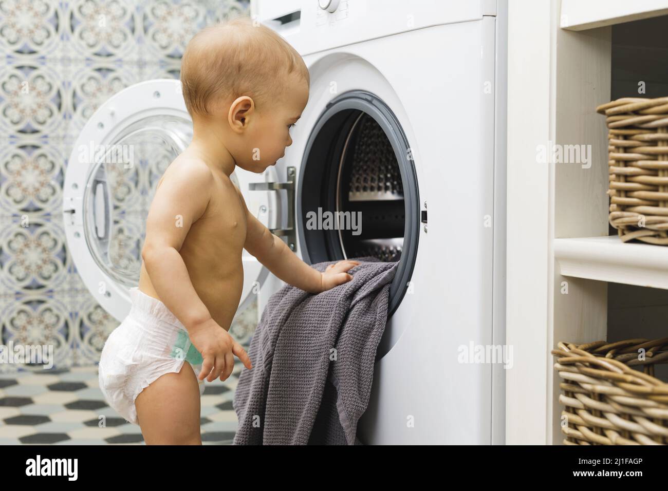 Cute baby boy is looking inside the washing machine Stock Photo - Alamy