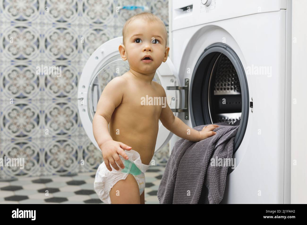 Cute baby boy beside the washing machine Stock Photo - Alamy