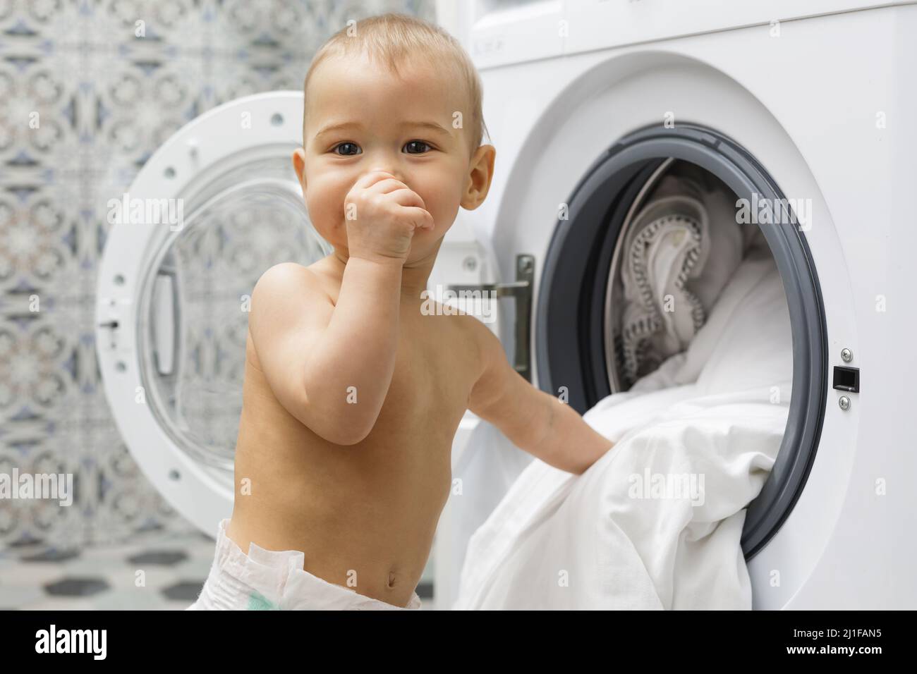 Cute baby boy beside the washing machine Stock Photo - Alamy