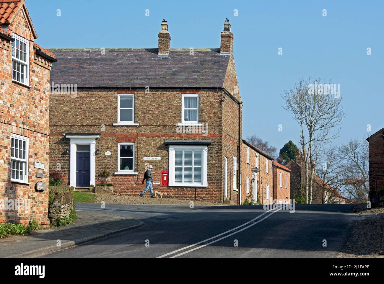 Man walking dog at road junction in the village of Crayke, North ...