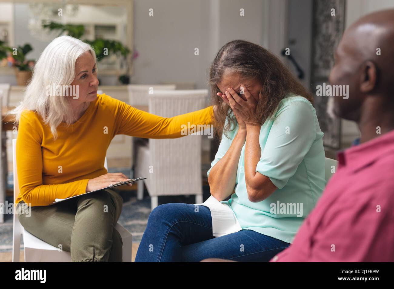 Caucasian senior woman consoling depressed female during group therapy ...