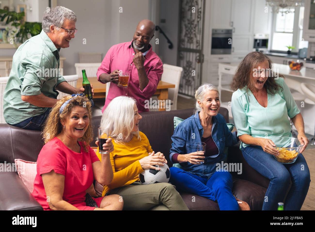 Multiracial senior male and female friends watching soccer match on tv ...