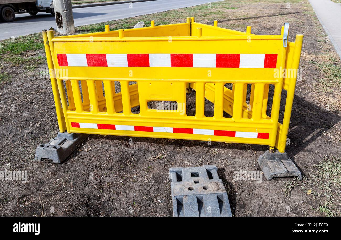 Yellow plastic fence with red and white strips at the city. Road works ...