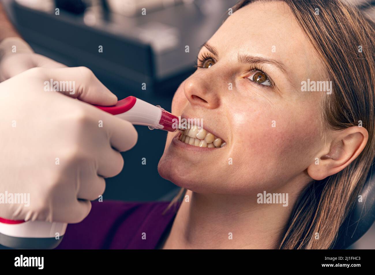 Dentist matching teeth color of woman with digital shade guide teeth ...