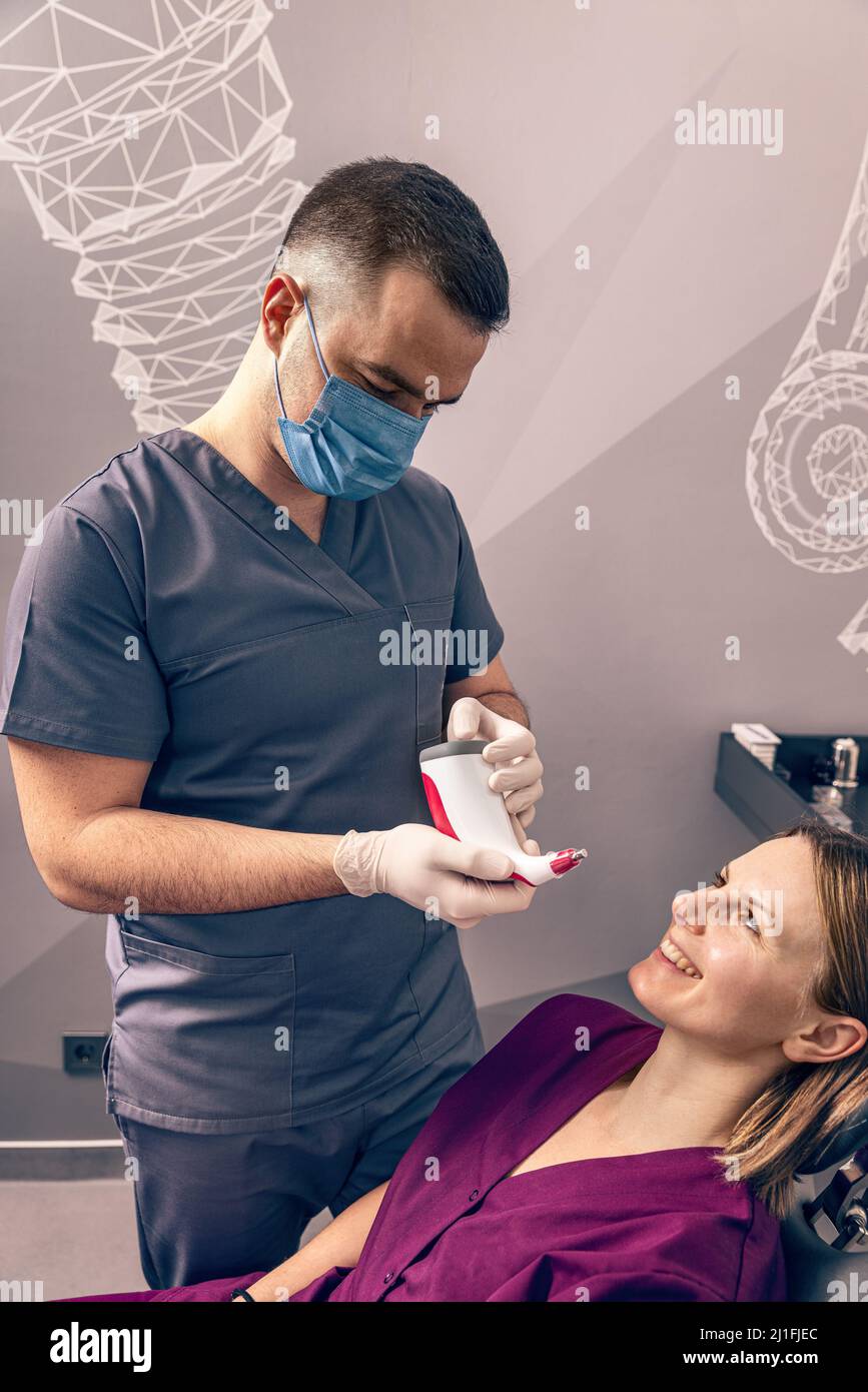 Dentist matching teeth color of woman with digital shade guide teeth ...