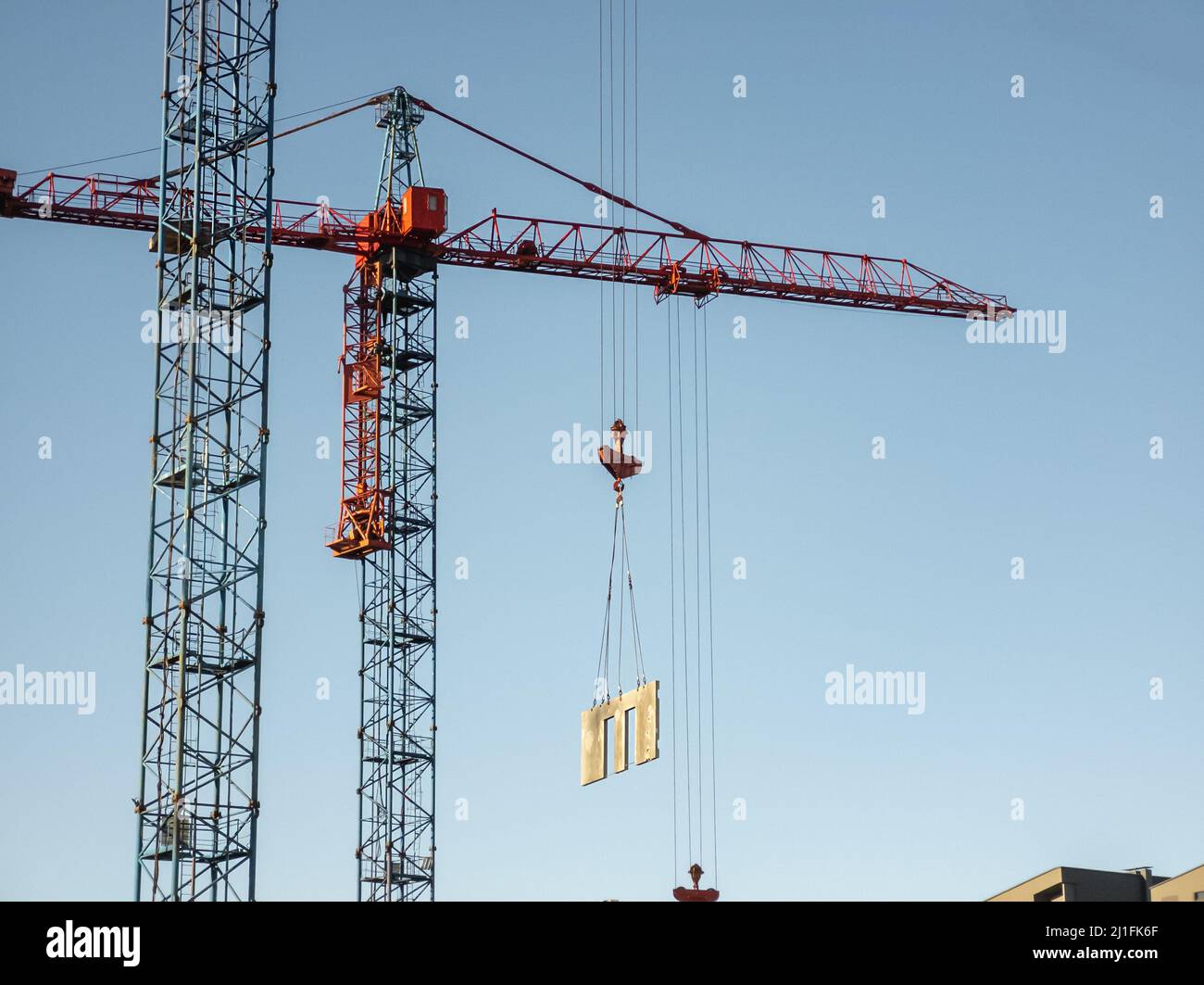 Tower crane delivers a concrete slab at a construction site ...