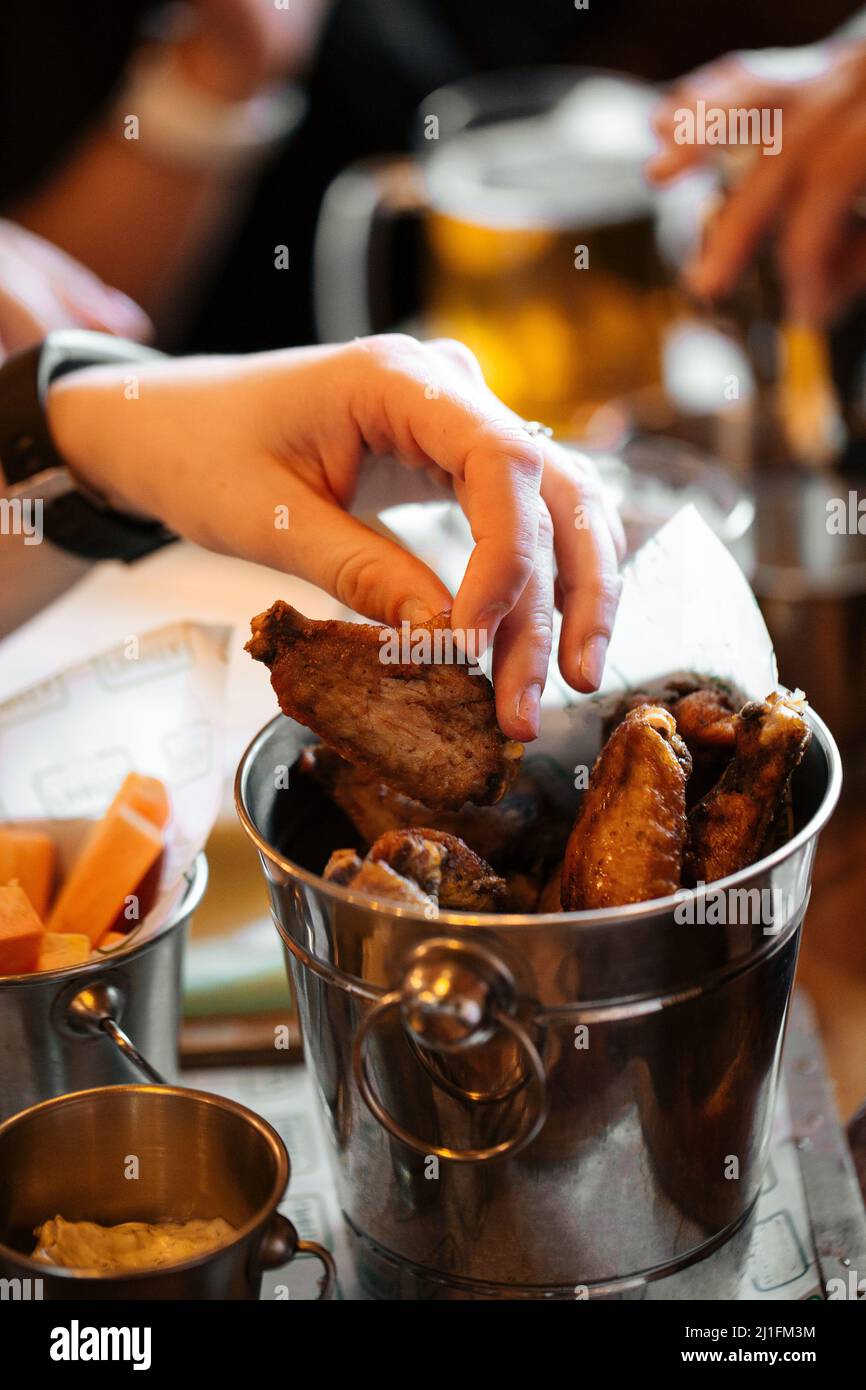 Hand taking baked chicken wing from a basket Stock Photo - Alamy