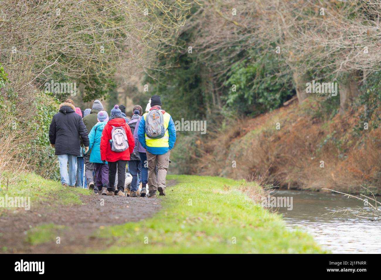 Rear view of an isolated group of ramblers walking alongside a UK canal ...