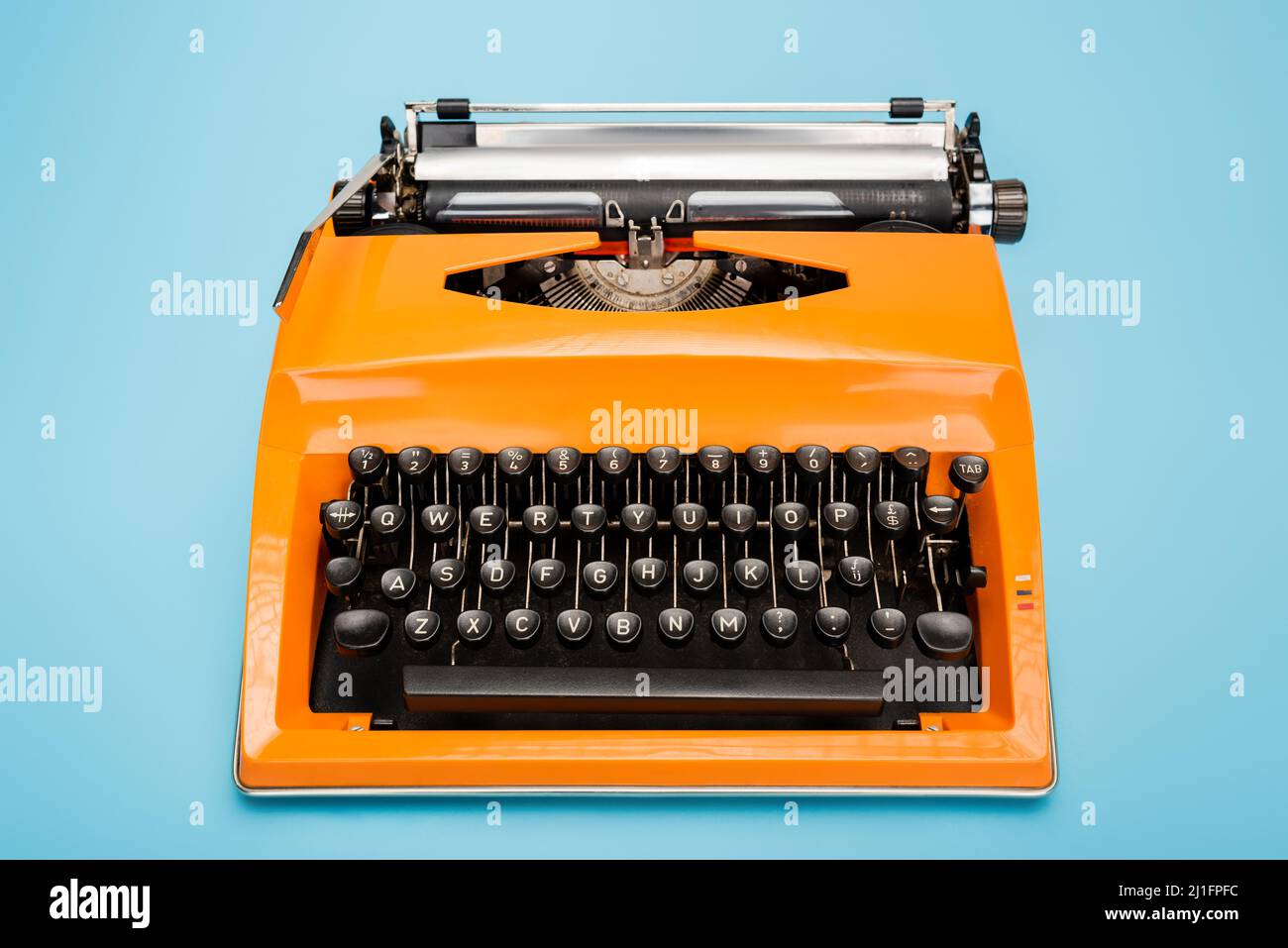 bright orange typewriter with black keyboard on blue background Stock ...