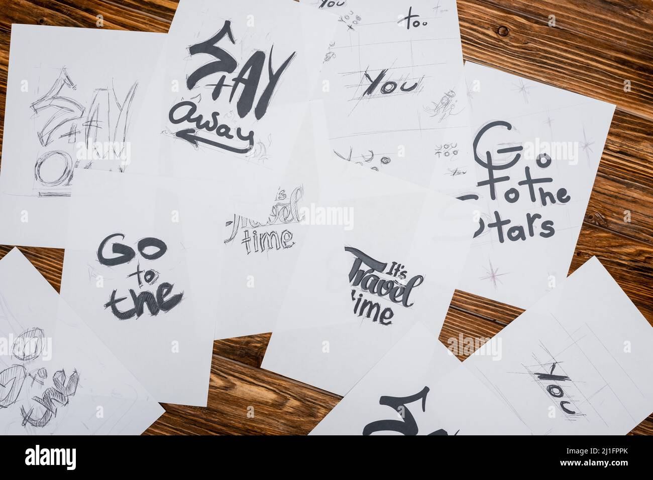 top view of white papers with various words and phrases on wooden desk ...