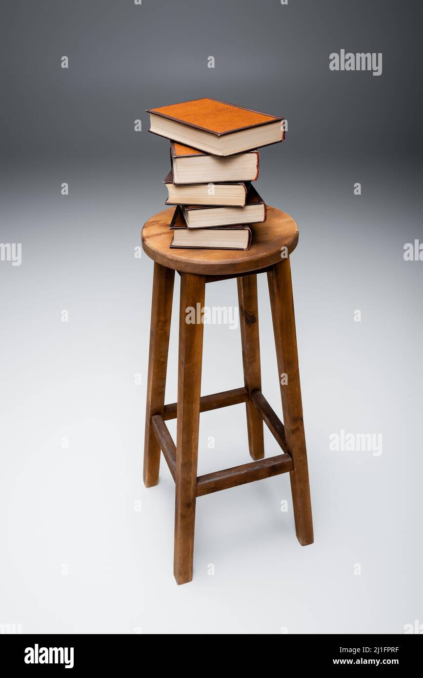 wooden stool with pile of books on grey background Stock Photo - Alamy