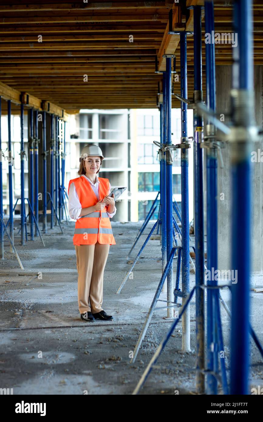 Confident Female builder checks fastenings on a monolithic structure ...