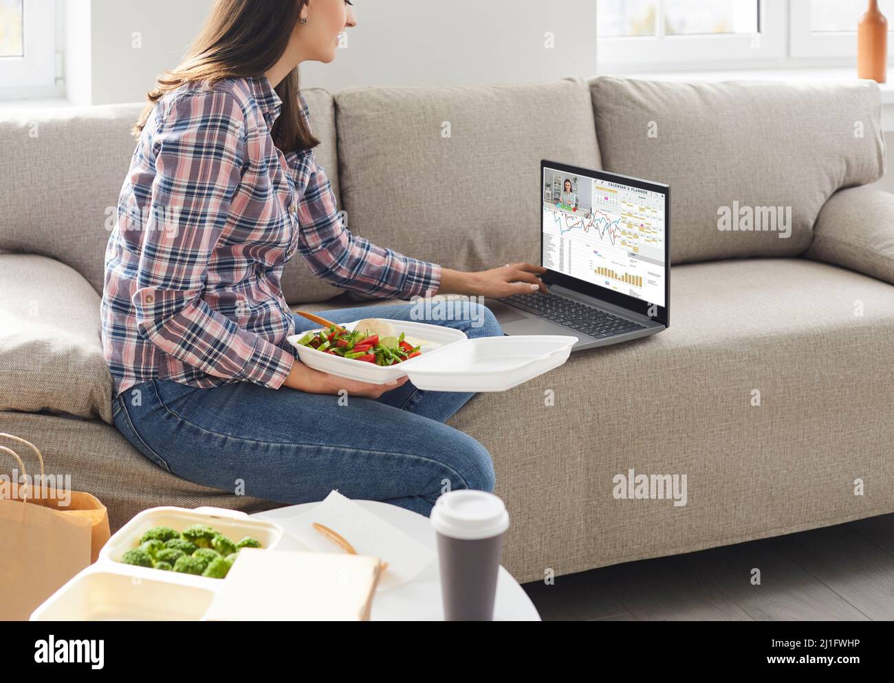 Remote employee having healthy takeaway lunch while working on her ...