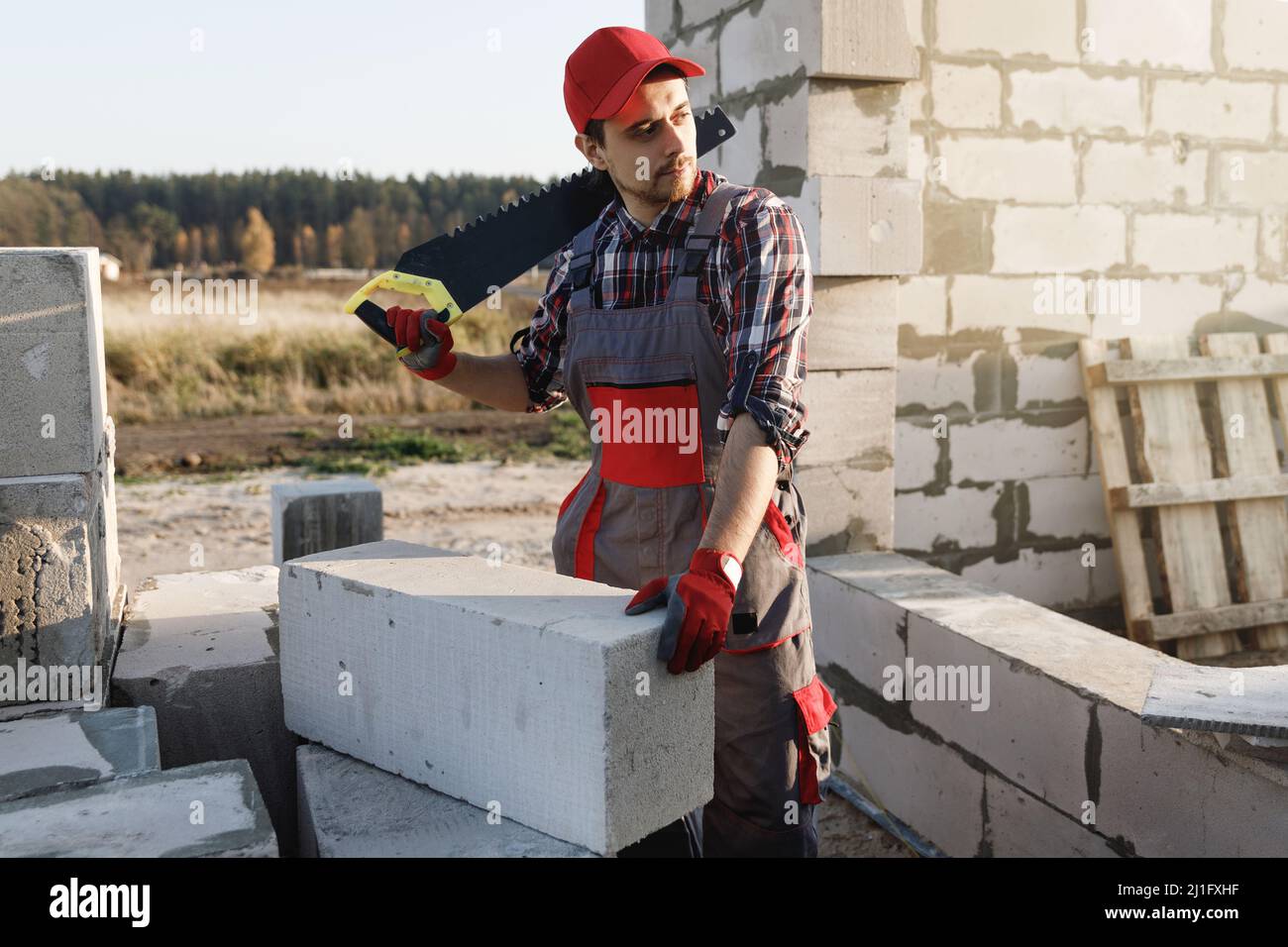 Bricklayer man is sawing autoclaved concrete blocks Stock Photo - Alamy