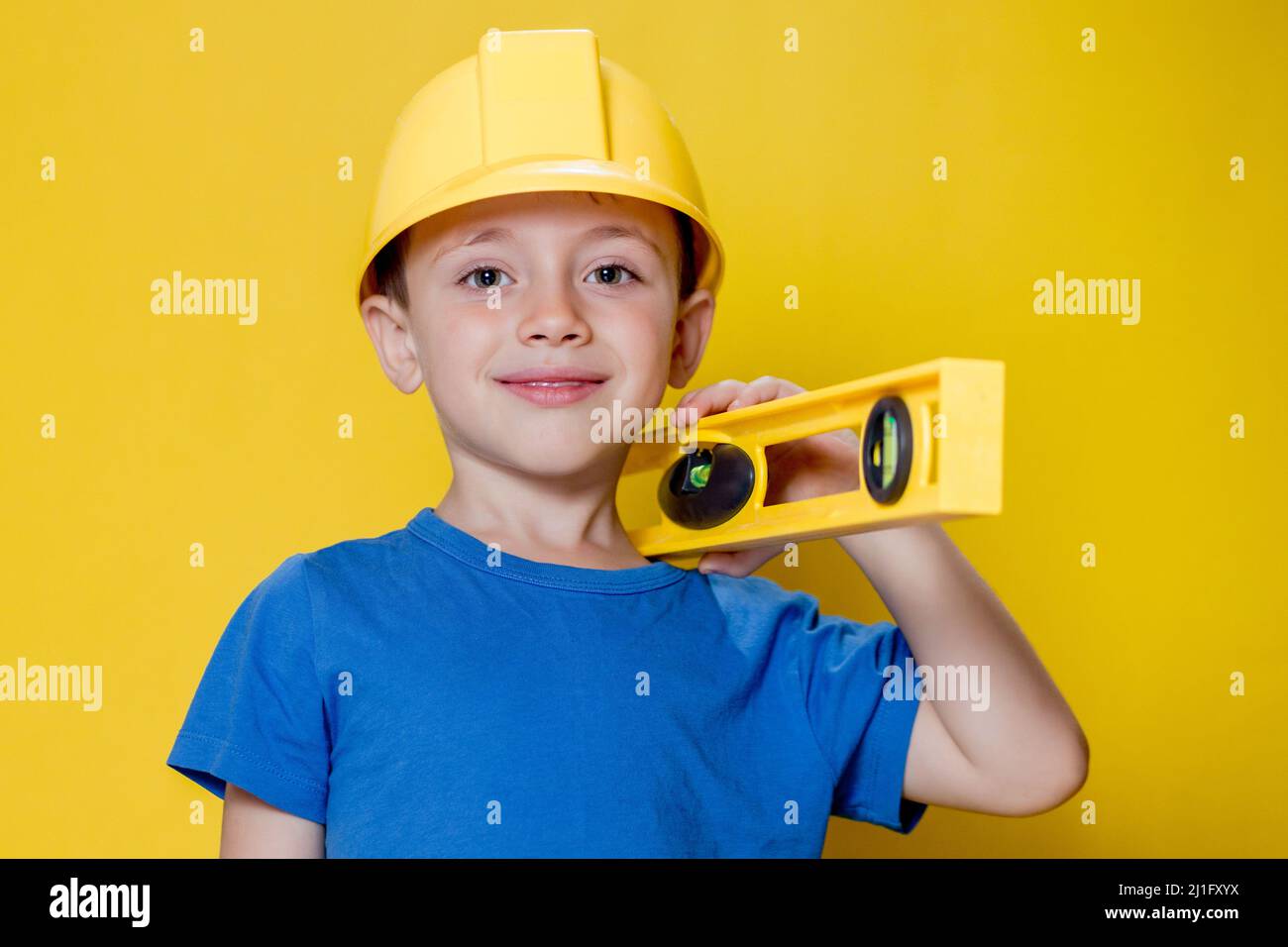 The preschooler in a helmet with a construction level plays a builder ...