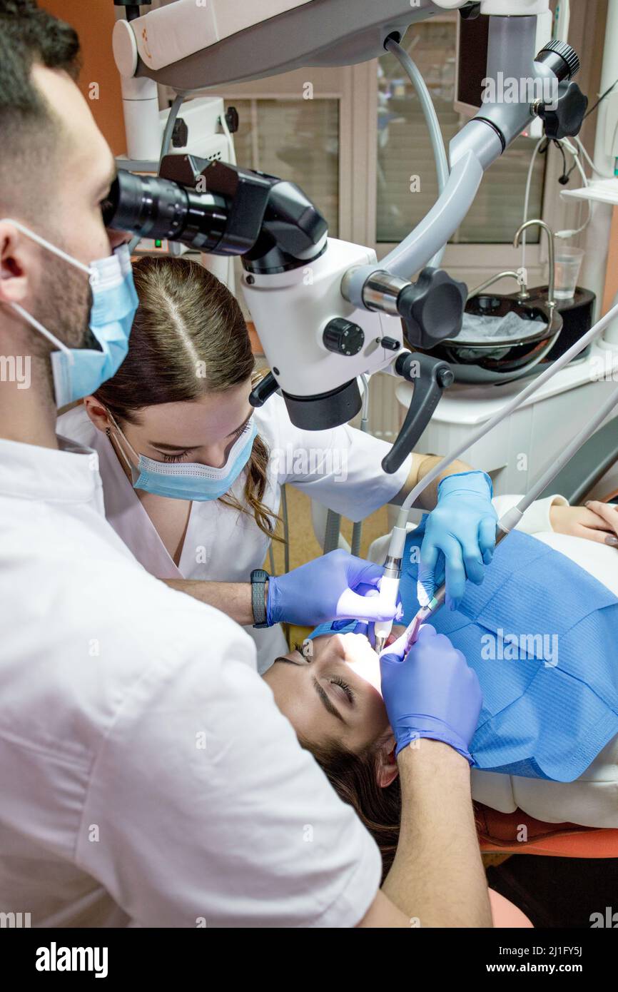 Dentist looking through a microscope at the patient's teeth. Modern ...