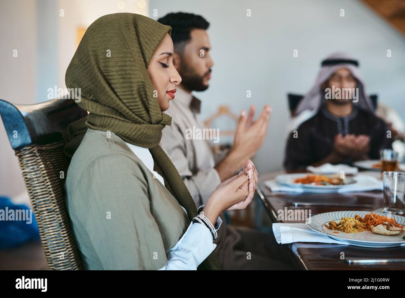 Giving thanks for a bountiful feast. Shot of a muslim family praying ...