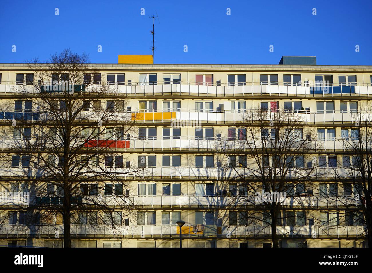 a photo of old apartment building behind trees Stock Photo - Alamy