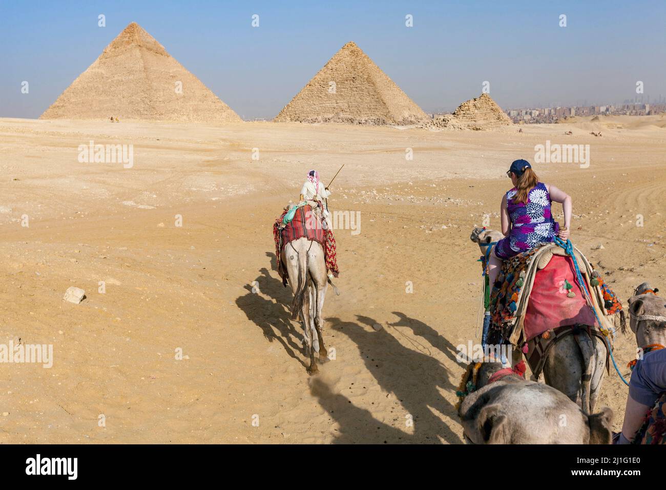 Tourists riding camels near the pyramids of Khafre and Menkaure, Giza ...