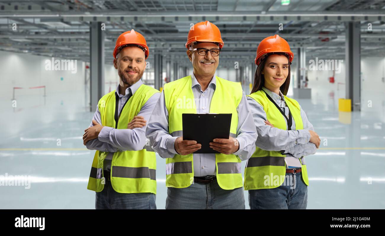Engineers wearing reflective vests and helmets and posing in an empty ...