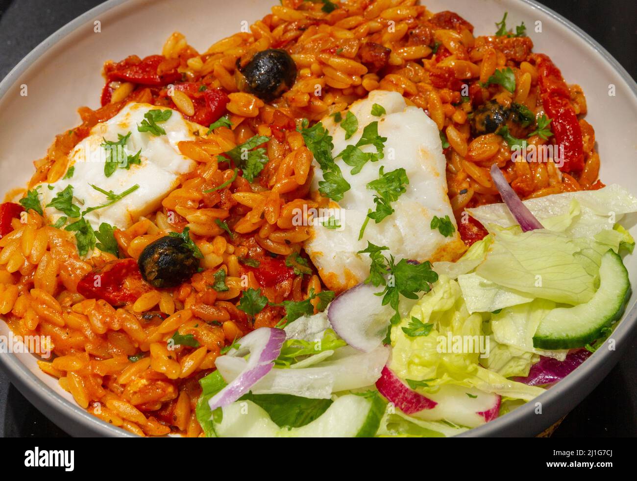 Baked cod with orzo and spicy sausage with salad Stock Photo - Alamy