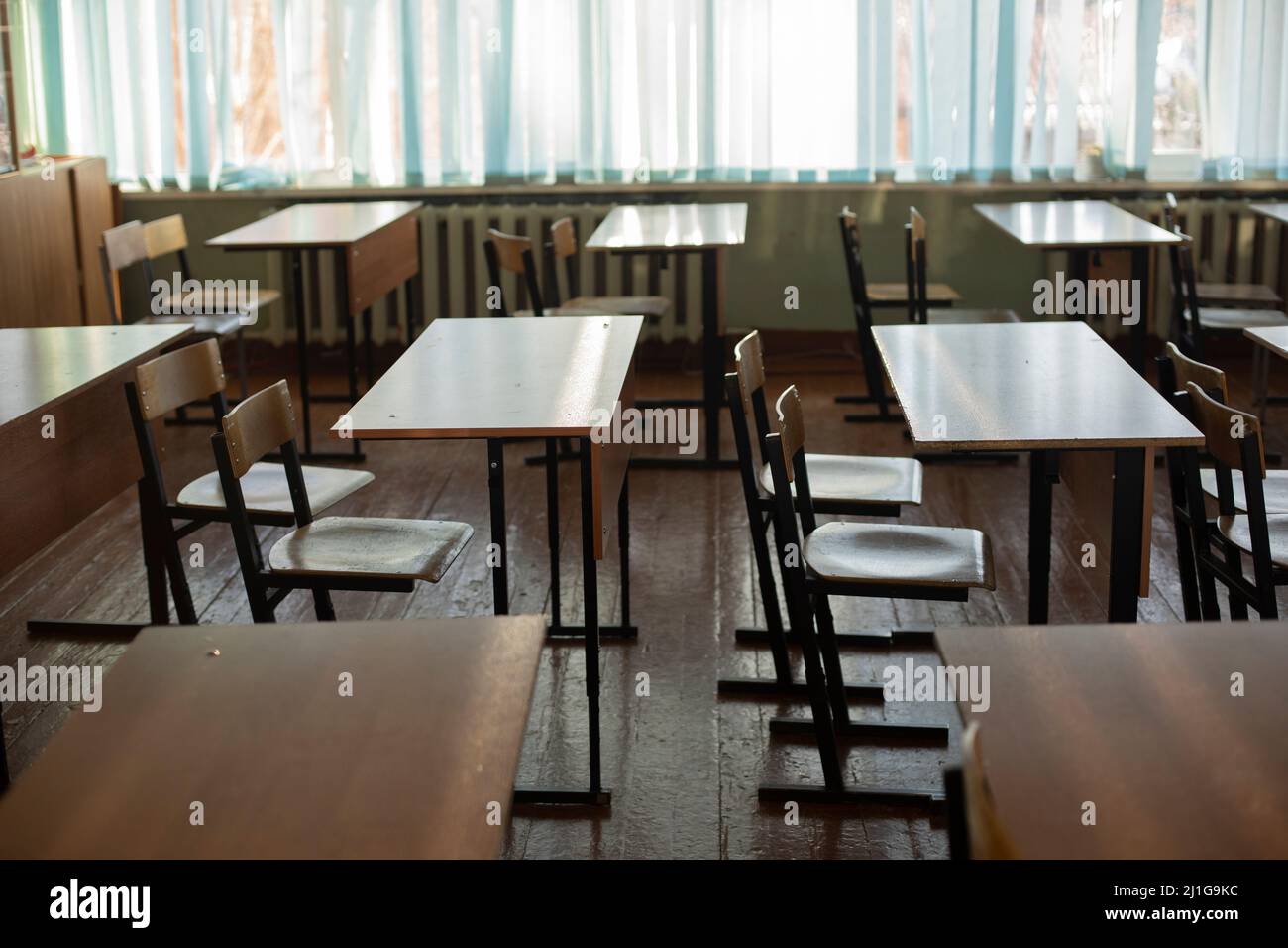 Desks for students at school. Classroom is empty. Chairs and tables are ...