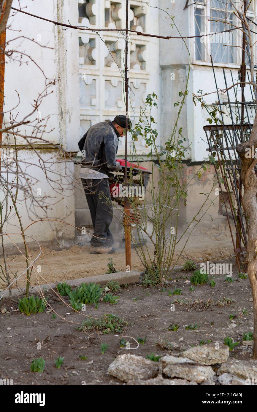 Worker uses a portable vibration rammer at construction a formwork for ...