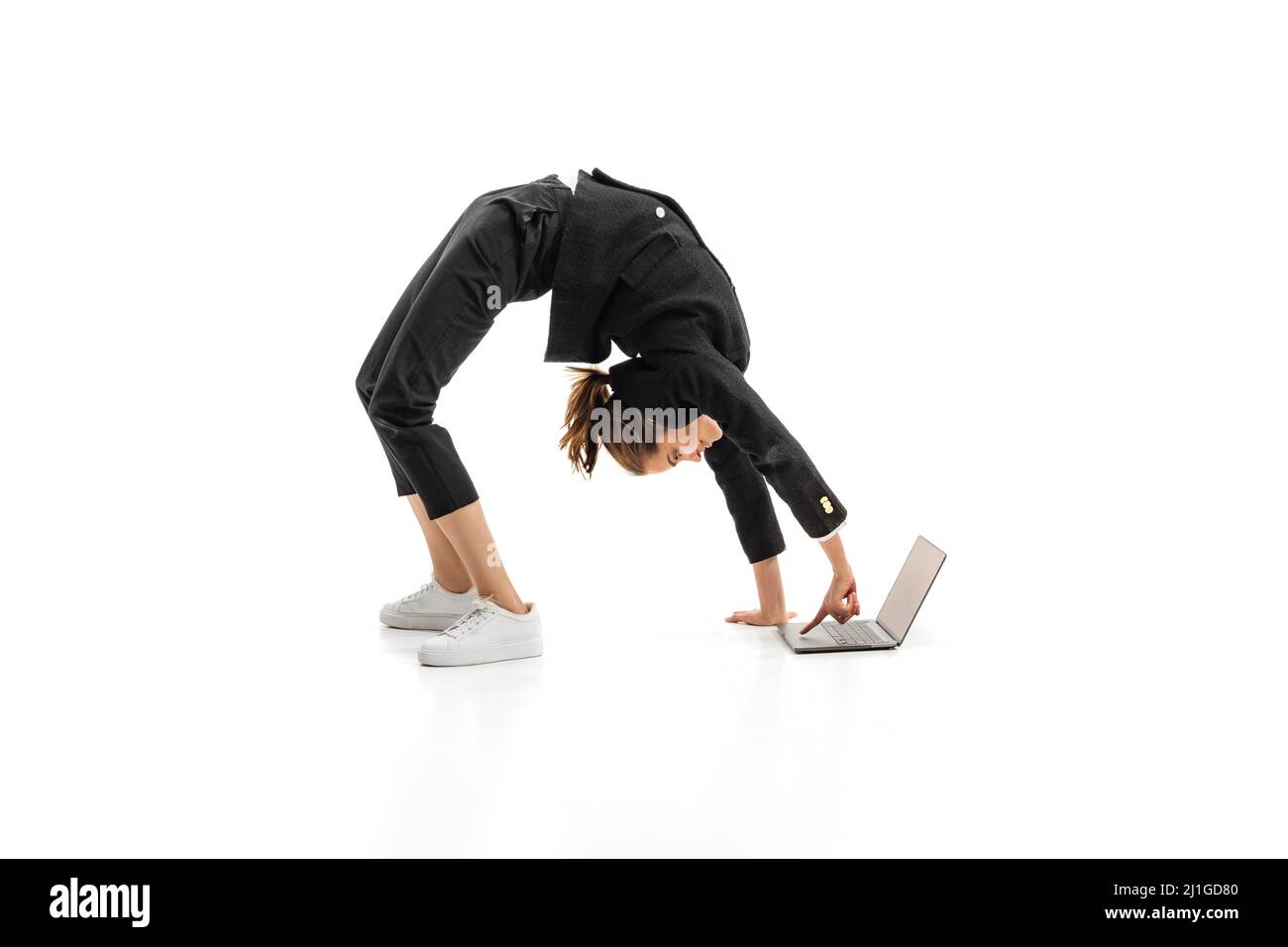 Dynamic portrait of young flexible woman doing backbend and typing on ...