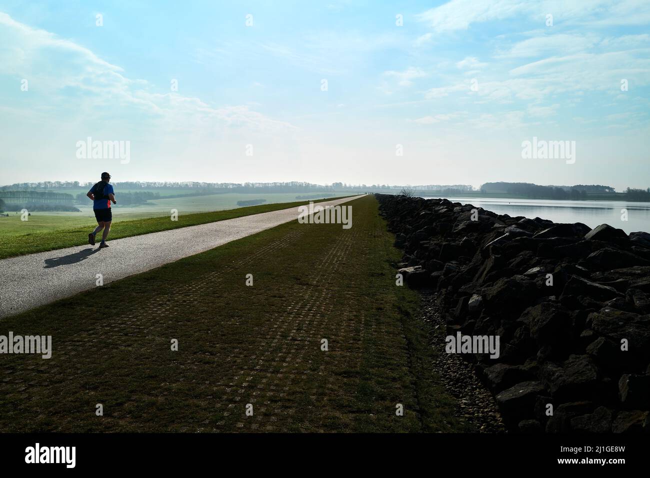 A sole male jogger on a path by a lake early in the morning Stock Photo ...
