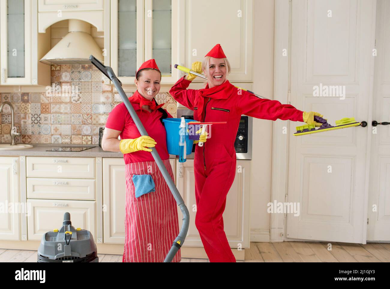 two girls cleaning company workers with a vacuum cleaner and chemicals ...