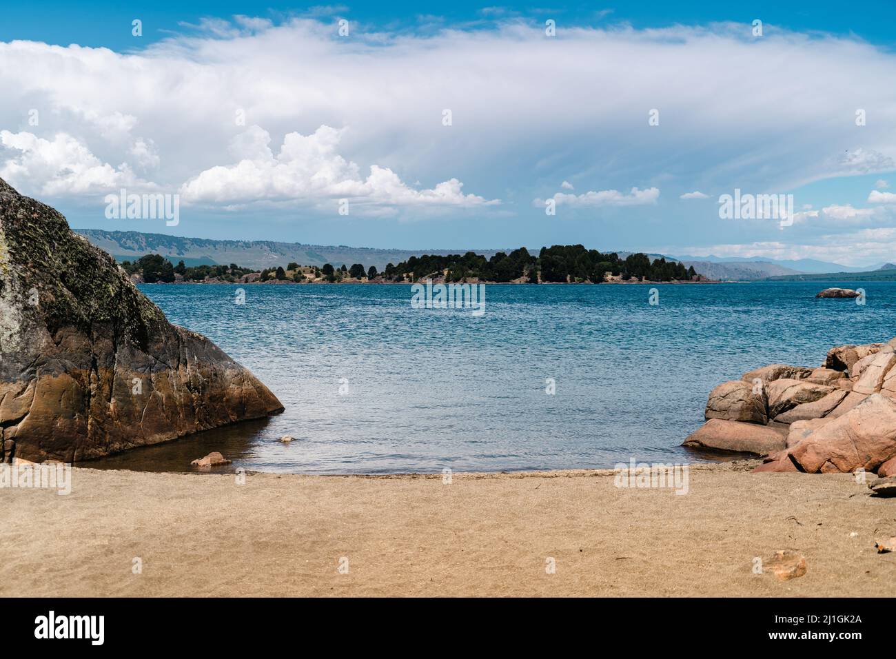 A beautiful scenery of the sandy beach with large rocks in the water ...