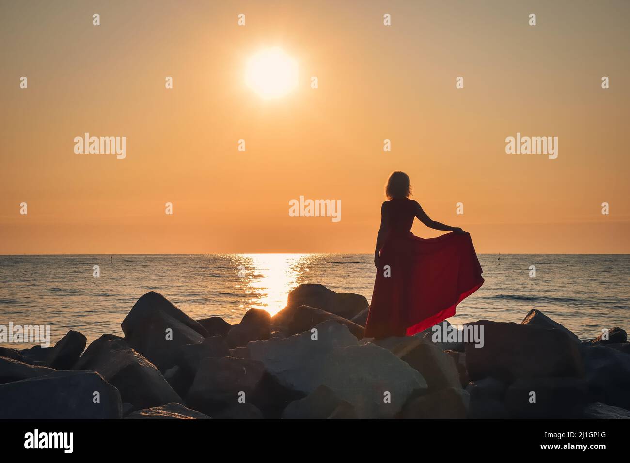 Beautiful seaside landscape with a woman on the beach. Girl in a red ...