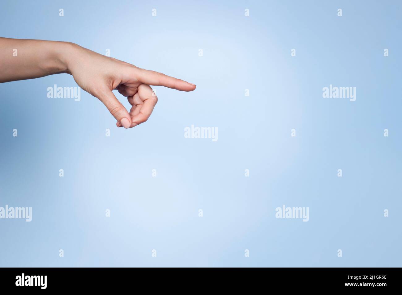 Woman hand gesture. Finger pointing to something on light blue ...